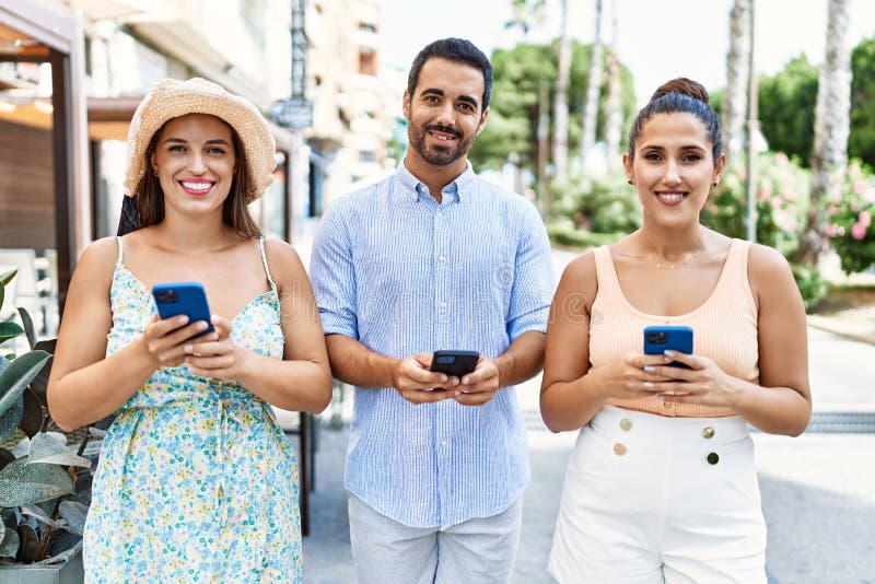 Three Hispanic Friends Smiling Happy Using Smartphone at the City Stock ...