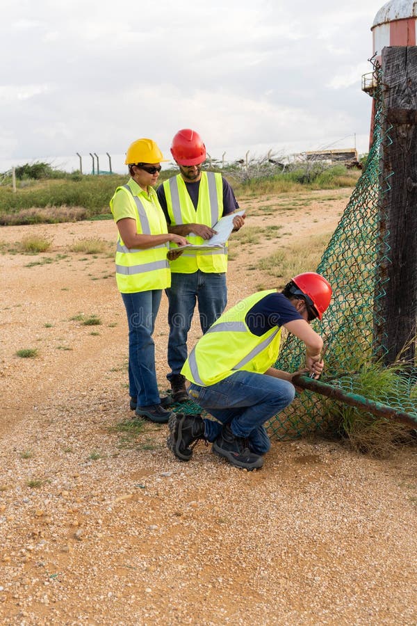 Three Industrial Workers at Work in Front of a Refinery Stock Photo ...
