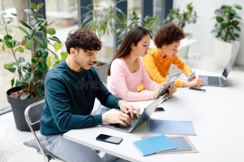 Three International Classmates Sitting at Table in Modern Auditorium ...