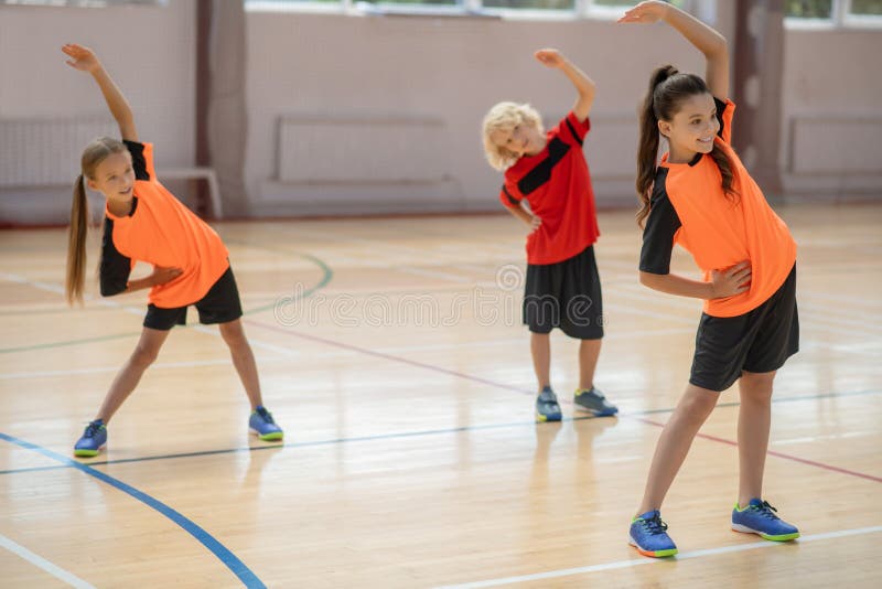 Three Kids Bending To the Right while Exercising in the Gym Stock Photo ...