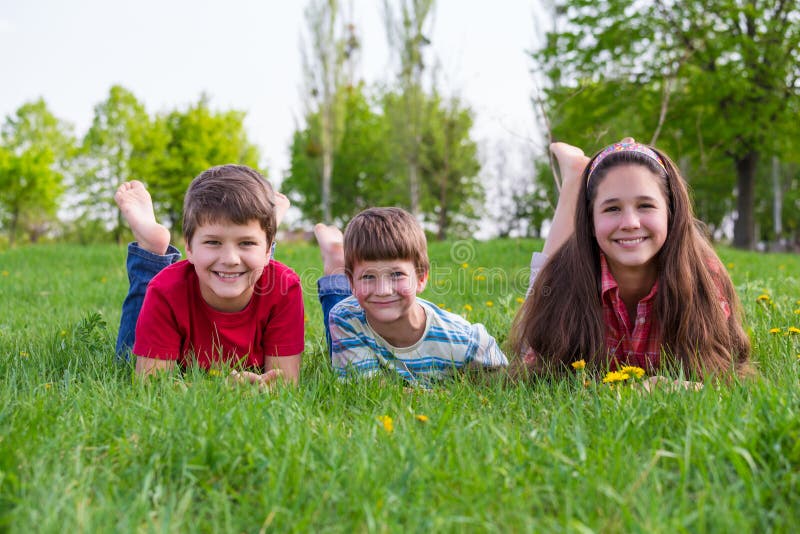 Three Kids Lying Together on Green Grass Meadow Stock Image - Image of ...