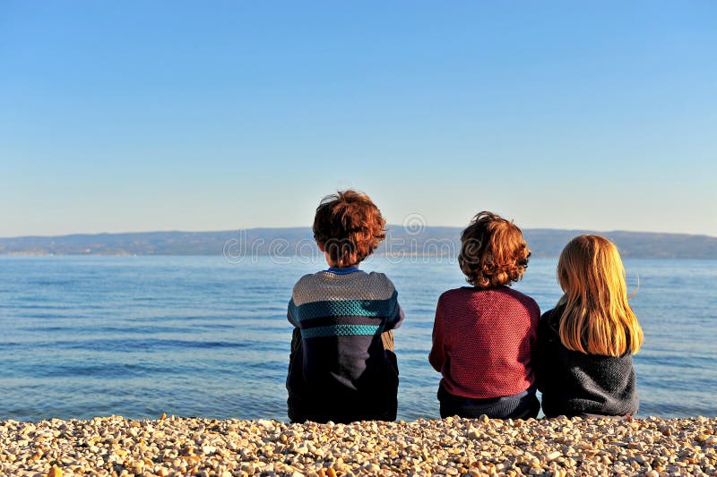 Three Kids Sitting on the Beach Stock Image - Image of beach, blue ...