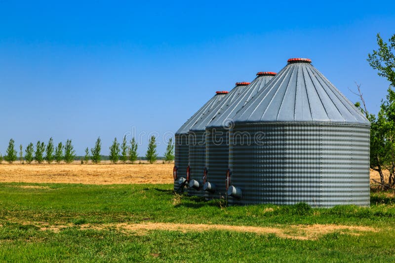 Three Large Metal Tanks Sit in a Field, with a Clear Blue Sky Above ...