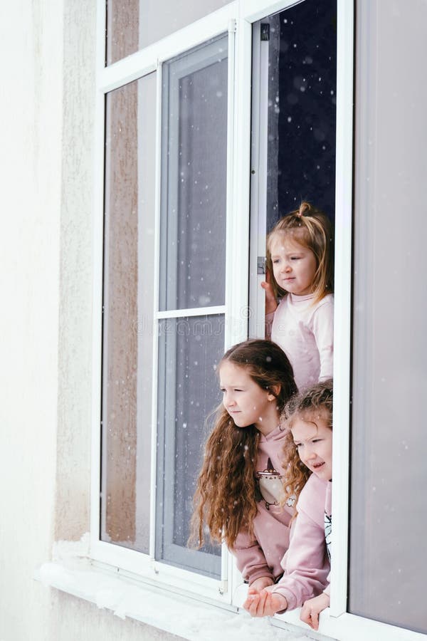 Little Girls Lean Out of the Window and Look at the Falling Snow Stock ...