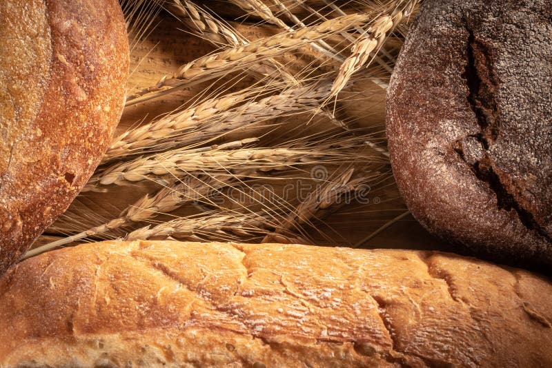 Three Loaves of Bread and Ears of Wheat on a Black Background Stock ...