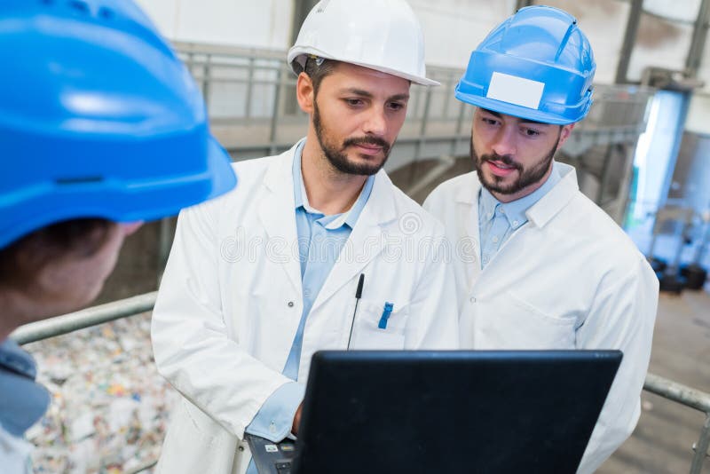 Three Male Workers in White Jackets Looking at Laptop Stock Photo ...
