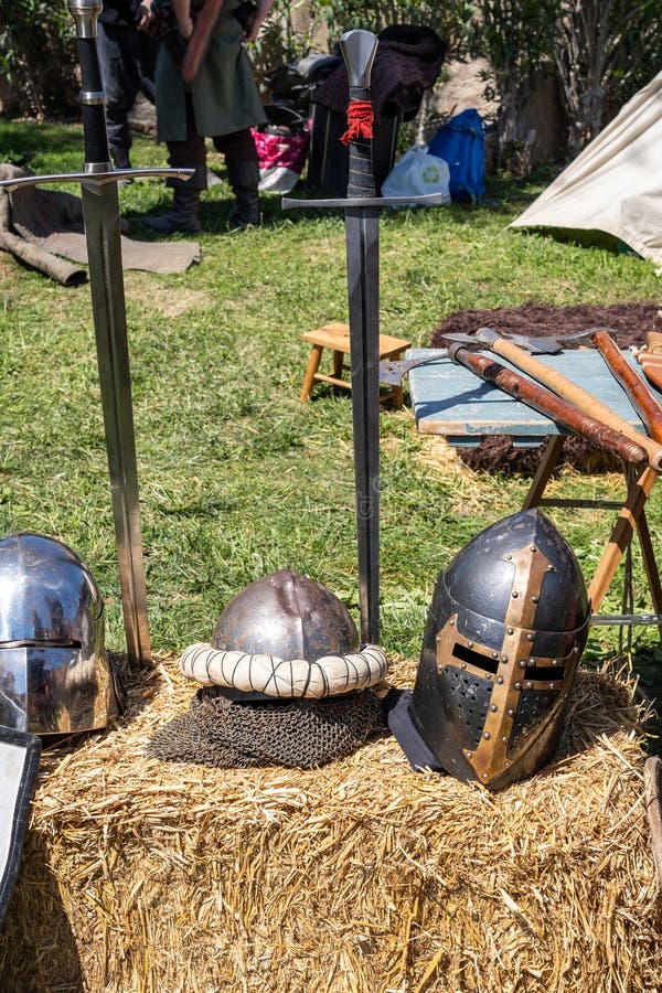 Three Medieval Helmets and a Sword are Displayed on a Hay Bale. the ...