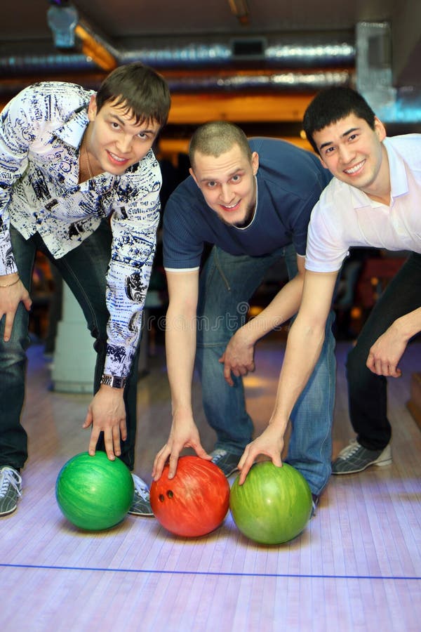 Three Men Bent Over To Heave Up Balls for Bowling Stock Image - Image ...