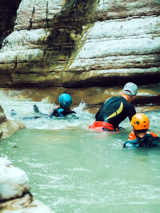 Three Men in Helmets and Wetsuits are Rafting Down the River Flowing ...