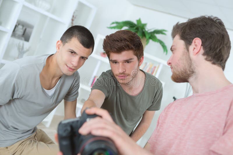 Three Men Looking at Photo on Camera Display Stock Photo - Image of ...