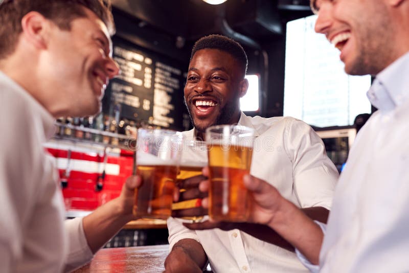 Three Men Making a Toast As they Meet for Drinks and Socialize in Bar ...