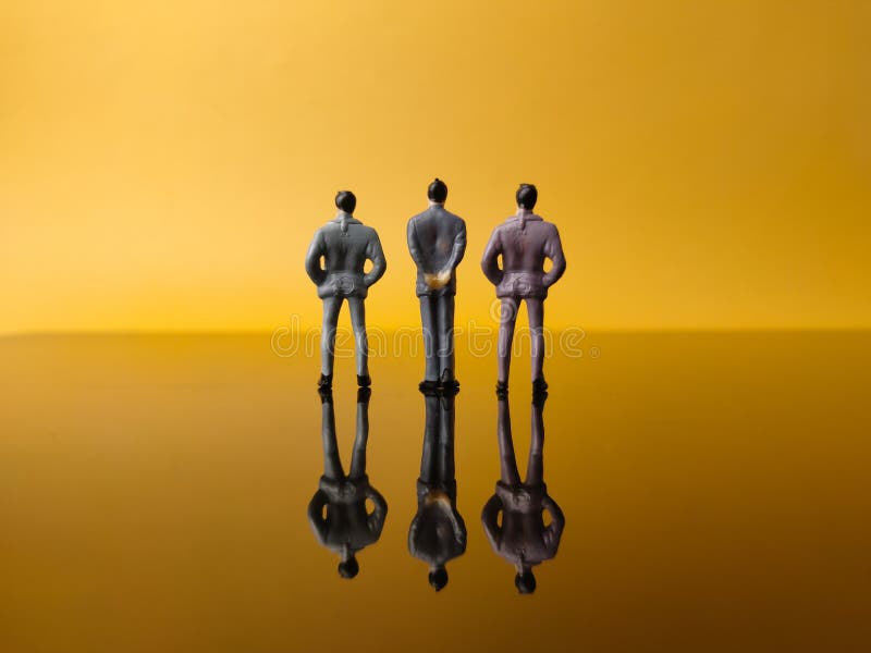 Three Men Miniature People with Reflection on a Yellow Background Stock ...