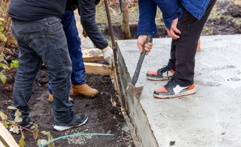 Three Men are Working on a Construction Site, One of Them is Holding a ...