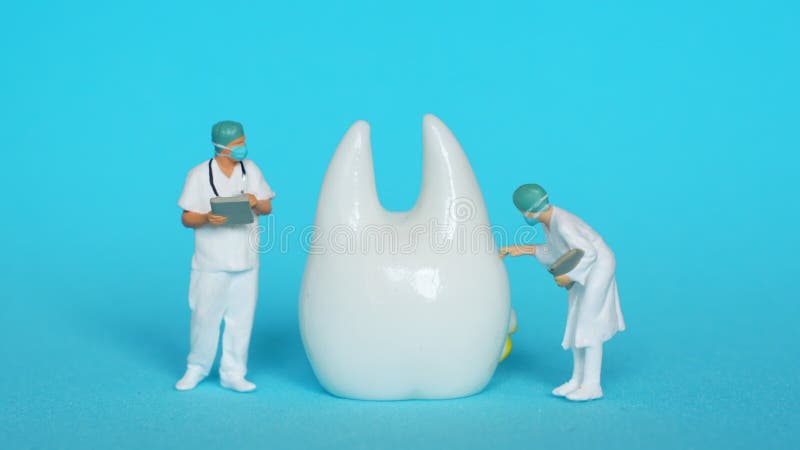 Miniature Dentists Working on Large Tooth Model with Blue Background ...