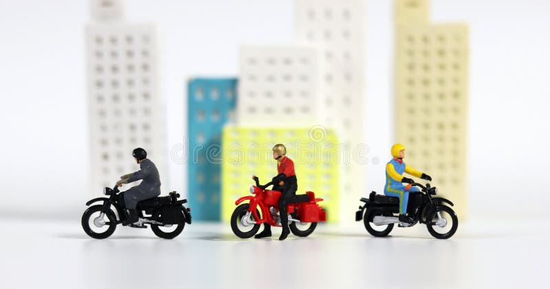 Three Miniature Motorcycle Riders in Front of a Miniature Building ...