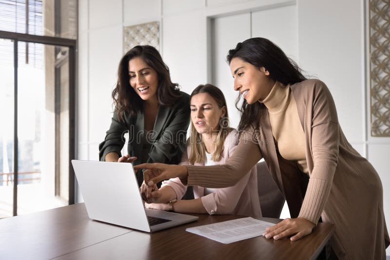 Three Multiethnic Women Colleagues Using Laptop Collaborate on Joint ...