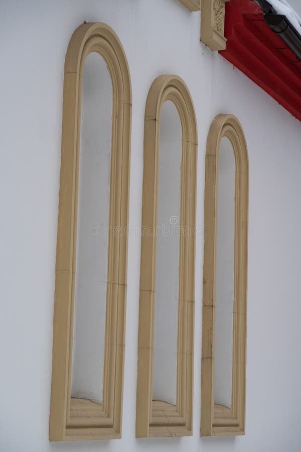 Three Narrow Arched Windows with Stone Trims on a White Plastered Wall ...