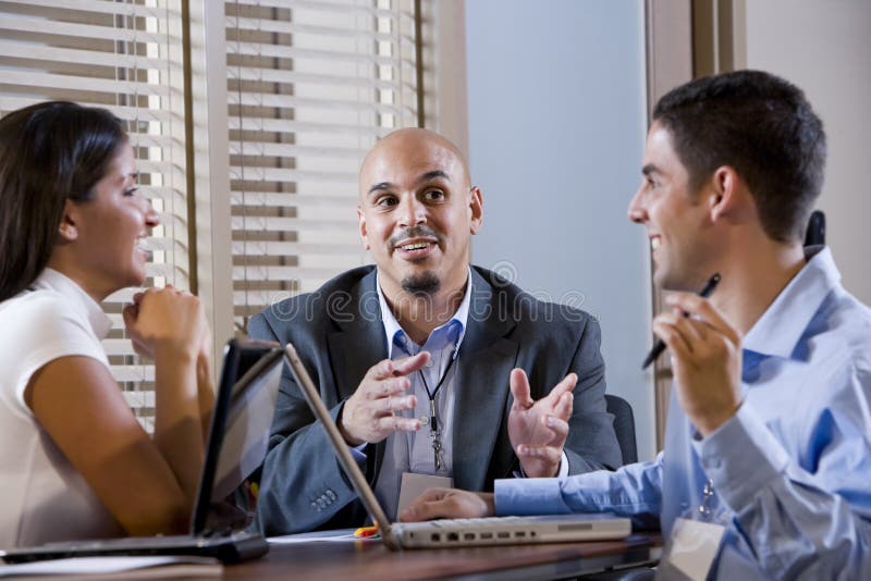 Three Office Workers Conversing at Desk Stock Photo - Image of hispanic ...