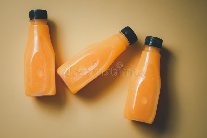 Three Orange Juices in Plastic Bottle on a Yellow Background Stock ...