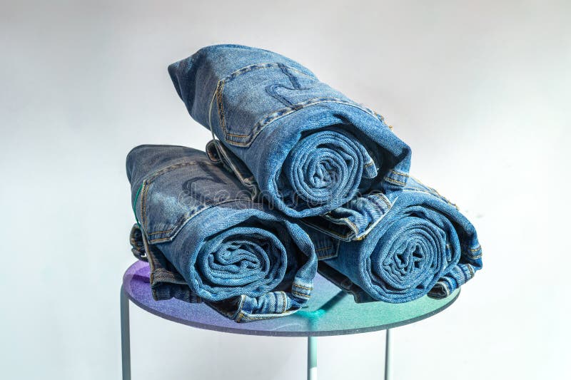 Three Pairs of Jeans Rolled into a Roll on a Stool Stock Image - Image ...