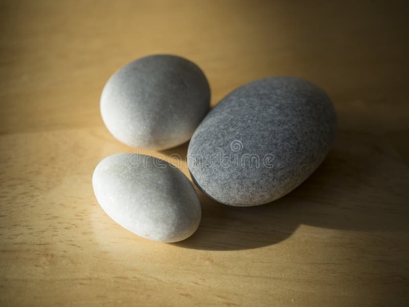 Three Pebbles - White and Grey on Natural Wood Desk Stock Photo - Image ...