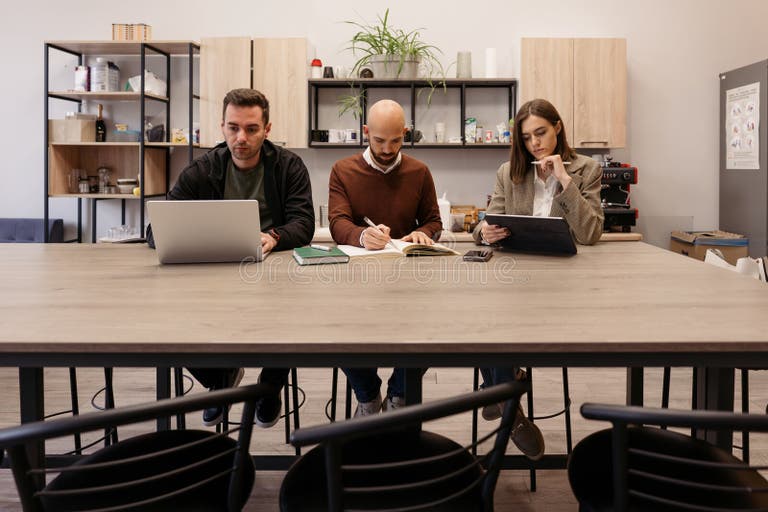 Three People in a Collaborative Workspace Engaged in Group Discussion ...