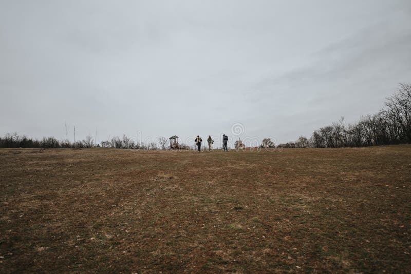 Three People Walking on a Wide Open Field Under an Overcast Sky Stock ...