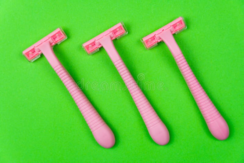 Three Pink Disposable Razors on a Green . Personal Hygiene Items for ...