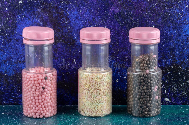 Three Plastic Bottles of Sprinkles and Candies on Blue Background Stock ...