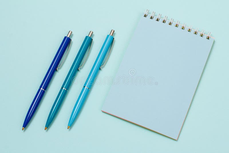 Three Plastic Pens and Notebook on a Blue Background Stock Image ...
