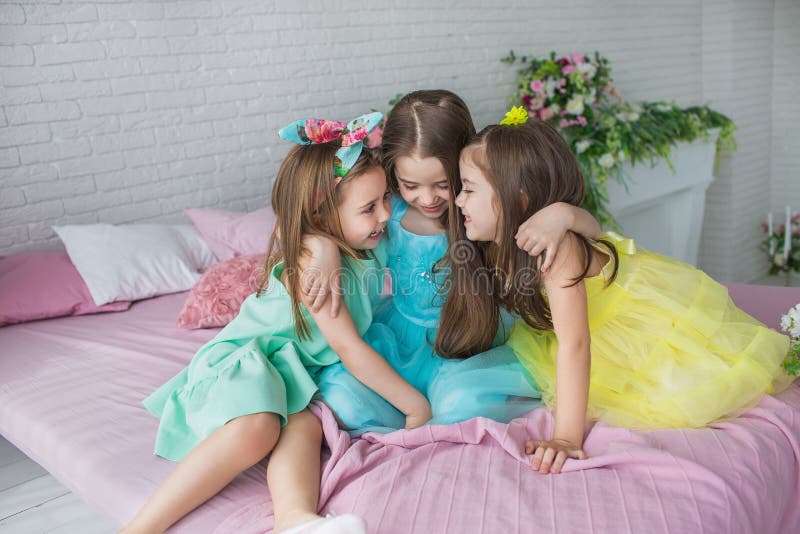 Three Pretty Little Girls Sit on a Bed and Hug Each Other Stock Image ...