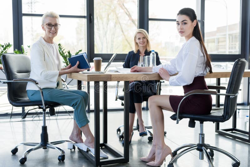 Three Professional Businesswomen Sitting at Table and Looking Stock ...