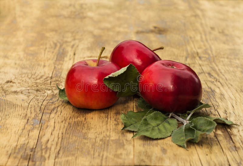 Three Red Apples with Leaves on a Light Wooden Background Stock Photo ...