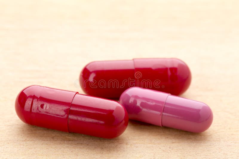 Three Red Capsules on the Wooden Table Stock Image - Image of bright ...
