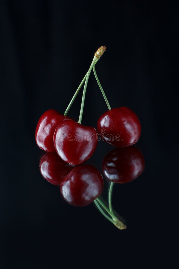 Three Red Cherries on a Black Background with Reflection. Fresh ... Three Red Cherries on a Black Background with Reflection. Fresh ...