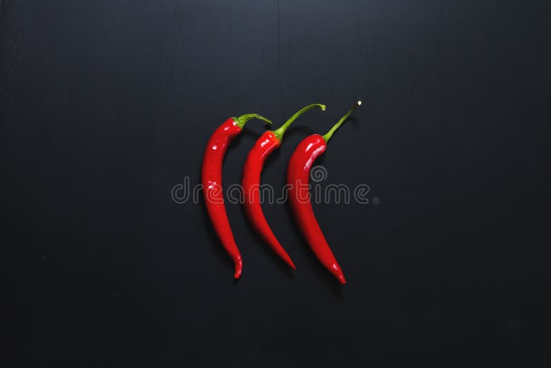 Three Red Chilli Peppers on a Black Background Stock Photo - Image of ...
