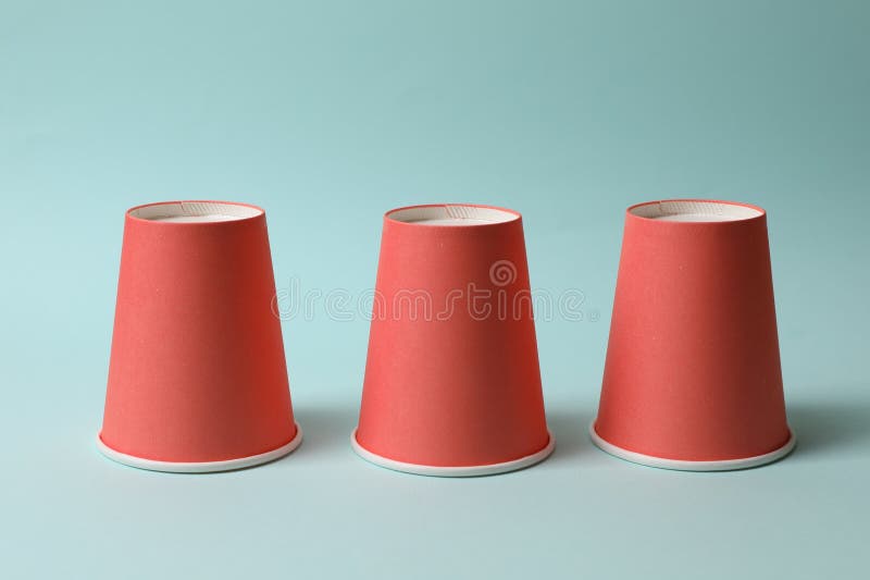 Three Red Cups on Light Blue Background. Thimblerig Game Stock Image ...