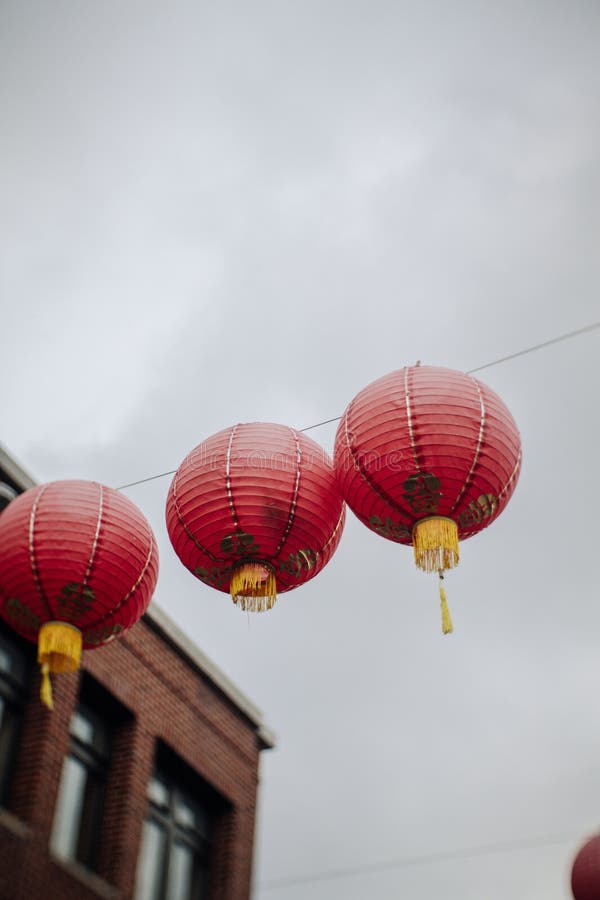 Three Red Paper Lanterns Hang in Front of a Brick Building Against a ...