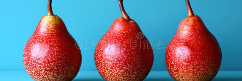 Three Red Pears with Spots on Them are Lined Up Against a Blue ...