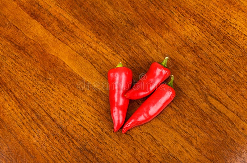 Three Red Peppers on Wood Table Stock Image - Image of spice, chilli ...