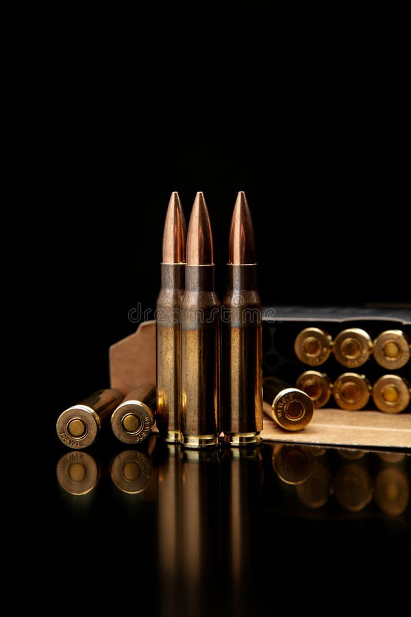 Three Rifle Bullets Standing Upright with a Box of Ammunition in the ...