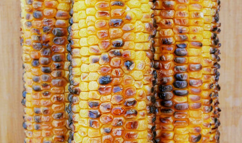 Three Ripe Fried Corn Lie Side by Side on a Wooden Background. View ...