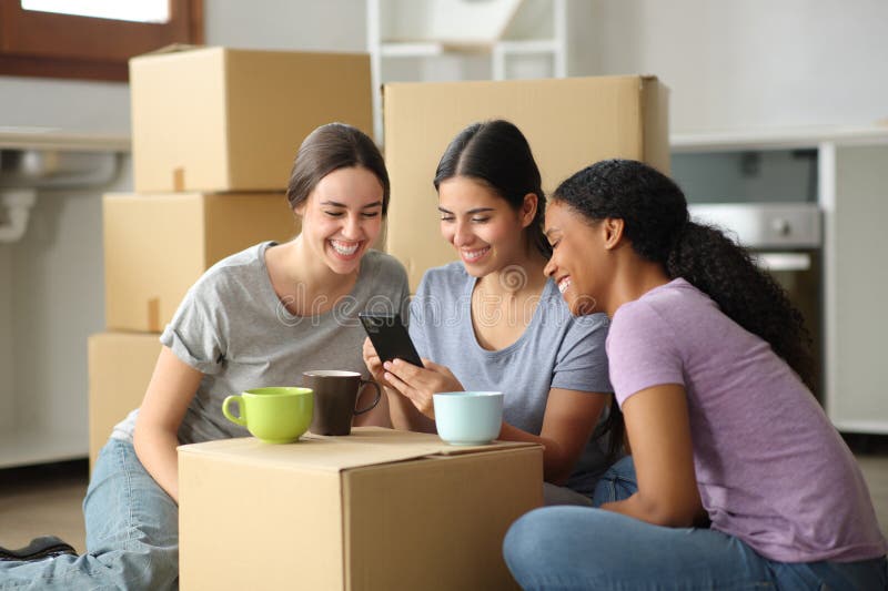 Three Roommates Checking Smart Phone Moving House Stock Image - Image ...