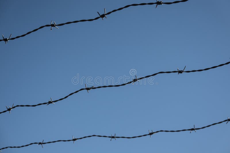 Three Rows of Rusty Barbed Wire in Front of a Blue Sky Stock Image ...