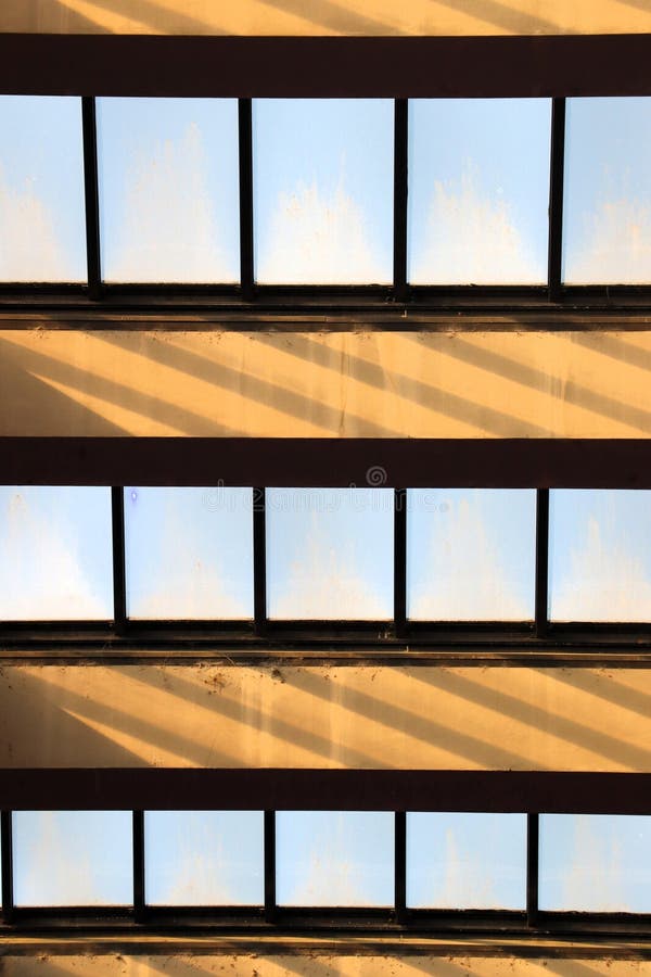 Three Rows of Windows Reflecting Blue Sky Divided by Gold Cement Strips ...