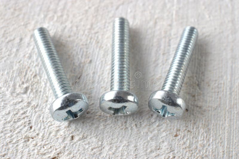 Three Screws on a White Wooden Table Stock Photo - Image of chrome ...