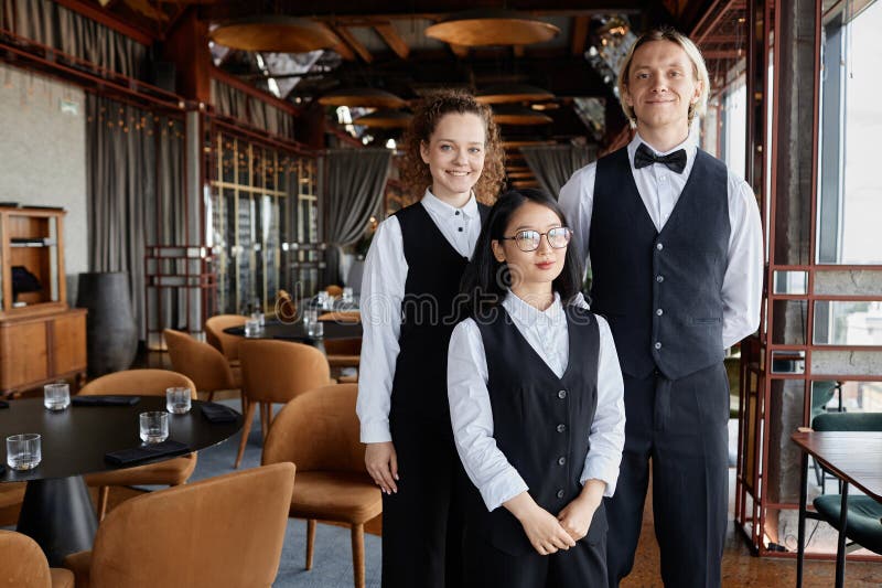 Three Servers Wearing Classic Uniform in Restaurant and Looking at ...