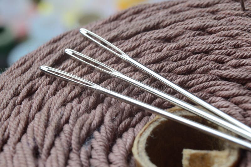 Three Sewing Needles Lie on a Brown Bobbin with Threads Stock Photo ...