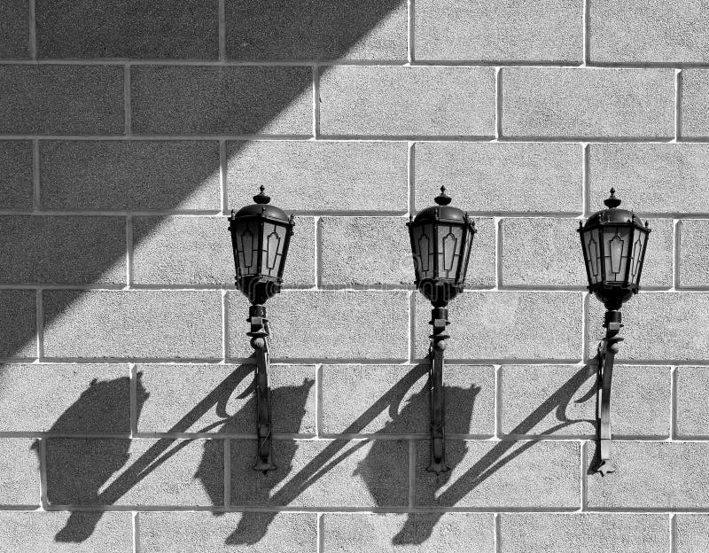 Three Similar Lanterns Attached To the Brick Wall Casting Symmetrical ...