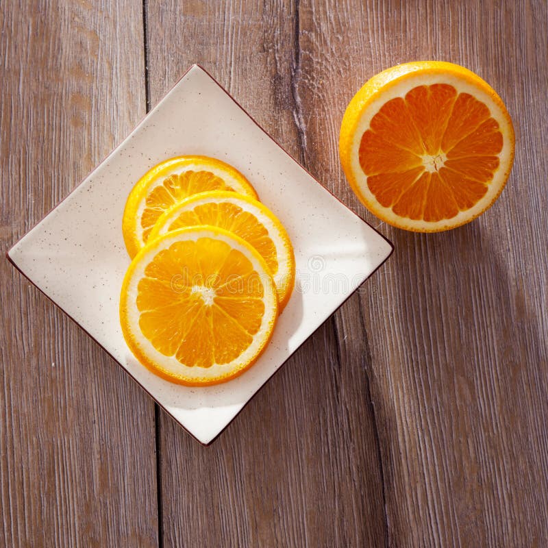 Three Slices of Orange on a Square Plate, Standing on Wooden Table ...